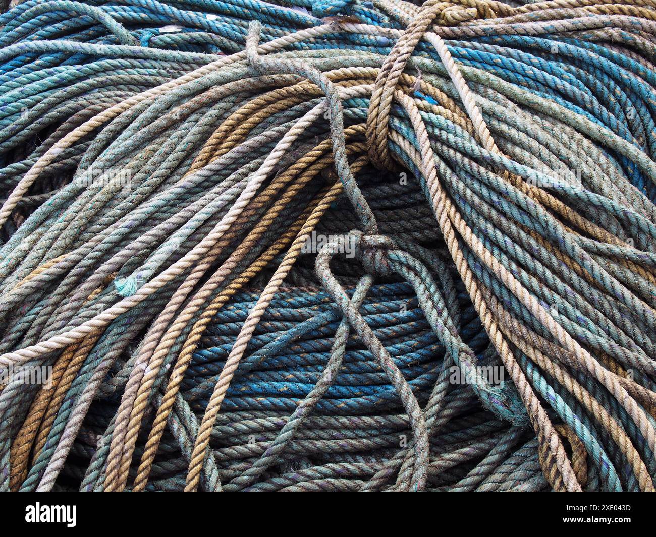 Stack of old blue coiled and knotted marine fishing rope in shades of ...
