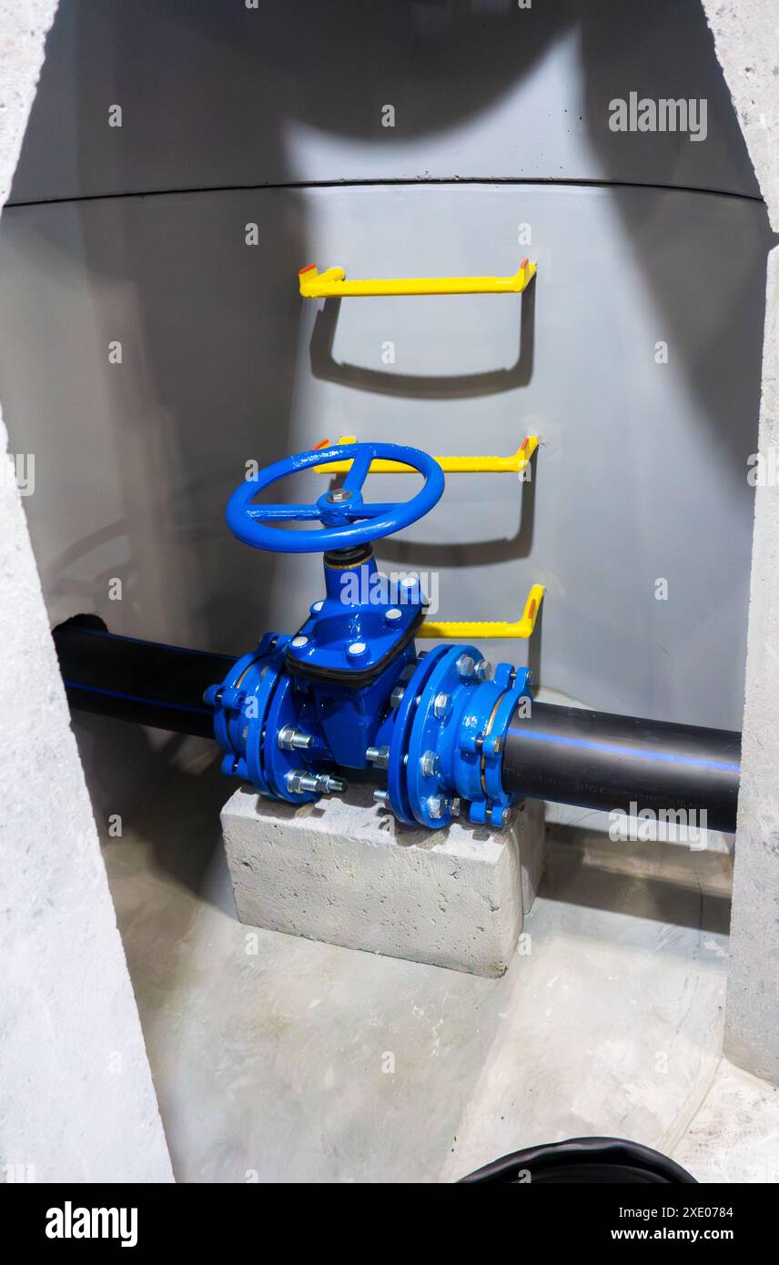 Concrete well with a hatch and a blue industrial valve for water ...