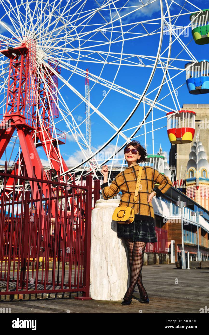 A happy woman enjoying a sunny day by the Ferris wheel, at Luna Park ...