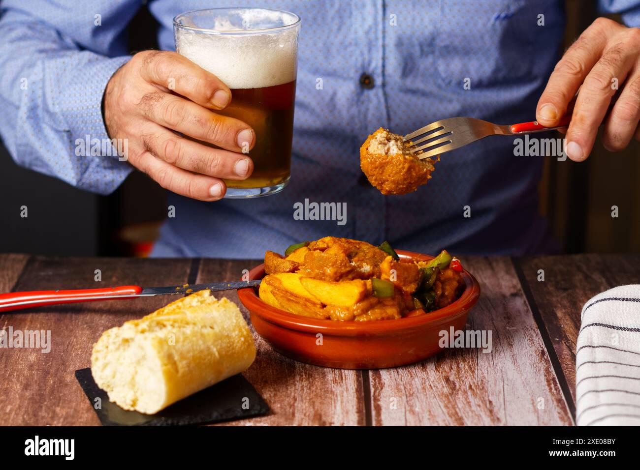 Man with beard eating meatballs with spaghetti with a glass of beer in ...