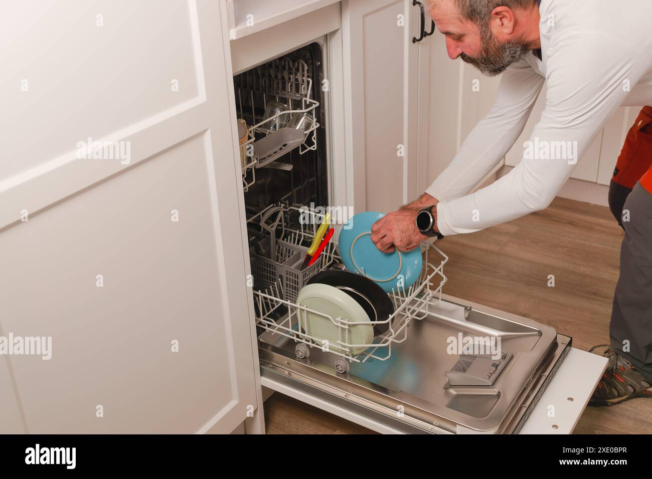 Man putting dishes in the dishwasher Stock Photo - Alamy