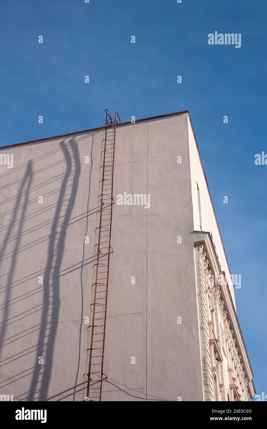 tall building facade featuring a metal ladder casting long shadows ...