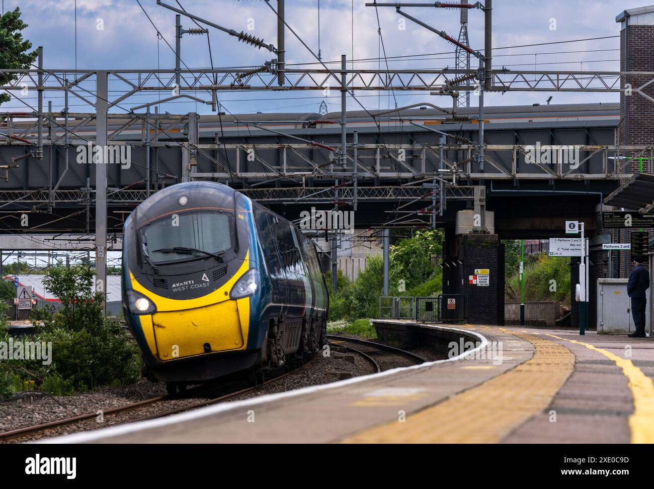 Pendolino train travelling at speed through a small station under ...