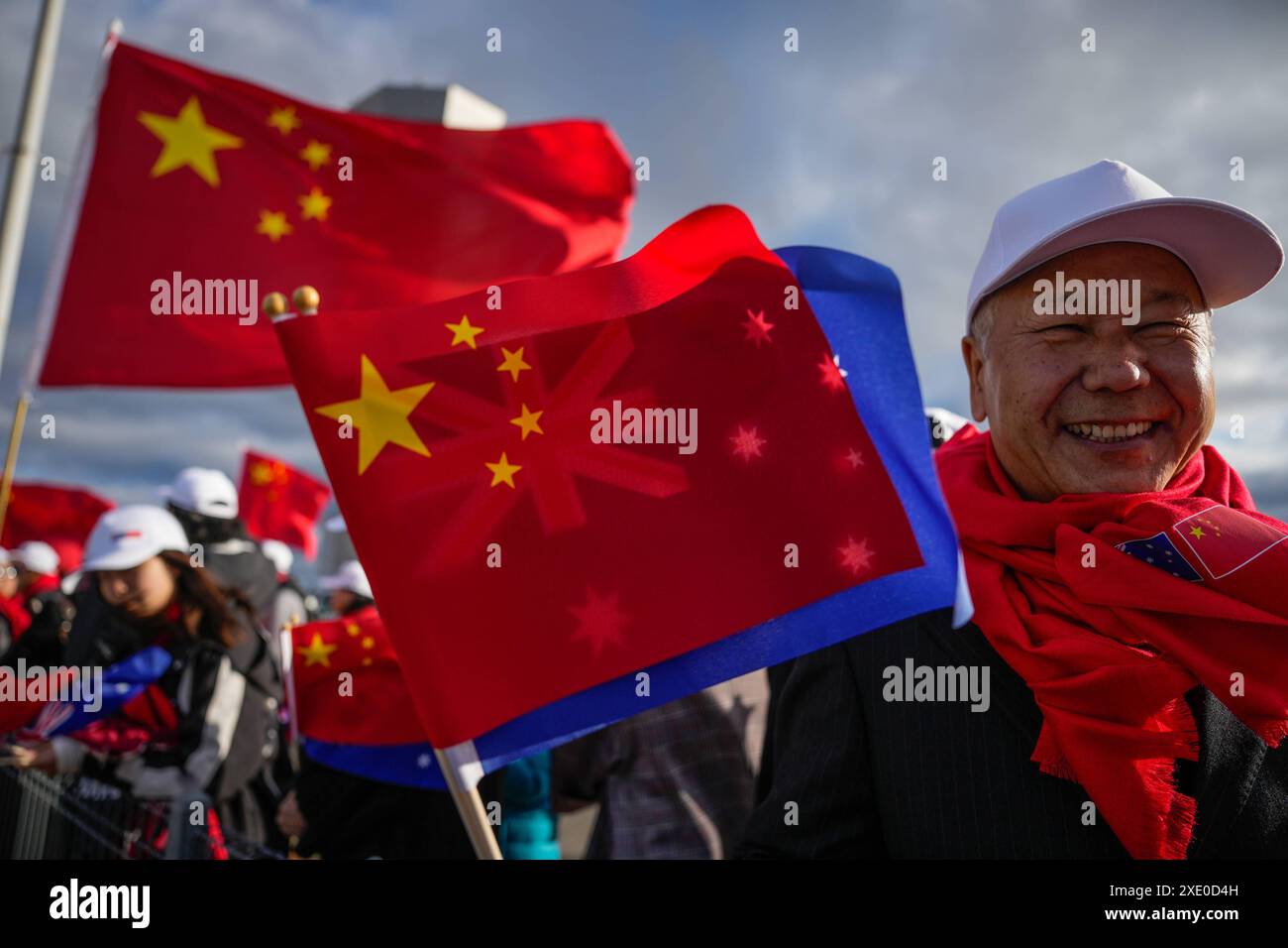 A man waves a Chinese national flag and an Australian flag as he awaits ...
