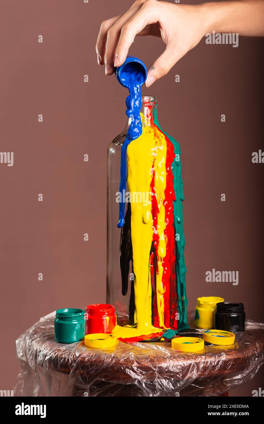 Painters hand pouring blue paint into a glass bottle. abstract art ...