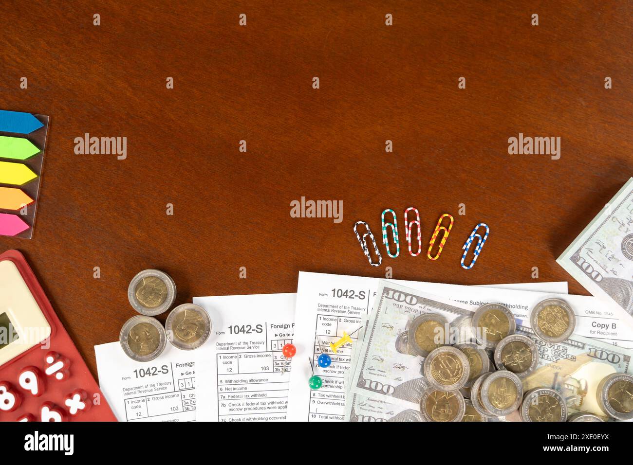 A table with a calculator, a stack of papers, and a pile of coins. US ...