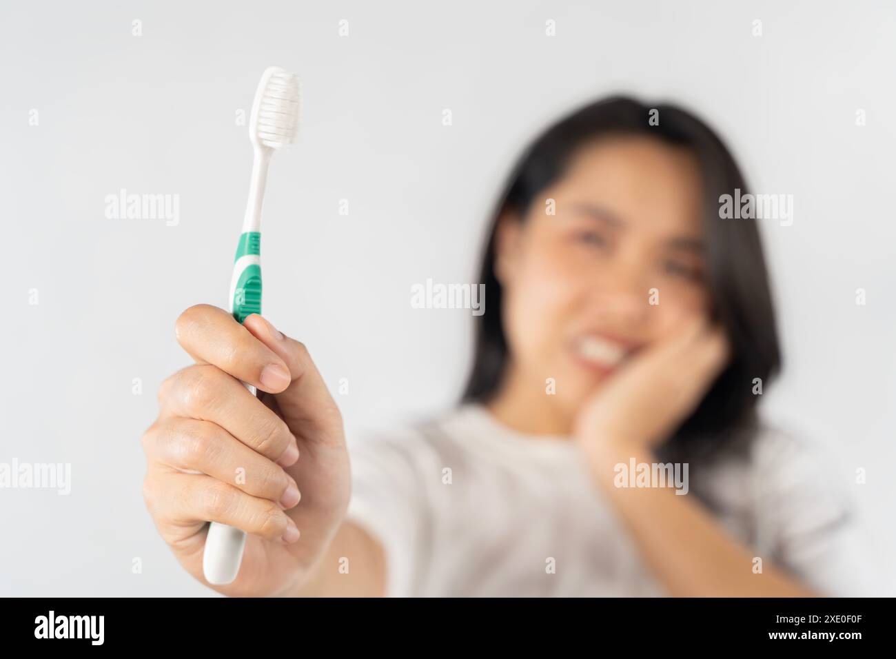 A woman is holding a toothbrush and smiling. Concept of cleanliness and ...