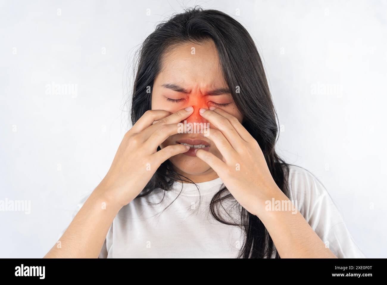 A woman with a red nose and eyes is rubbing her nose. She is in pain ...