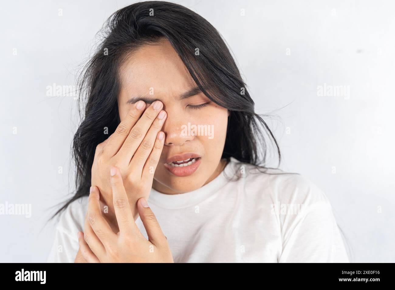A woman with her eyes closed and her hands on her face. She looks tired and exhausted. Concept ...