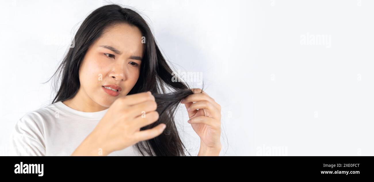 A woman with long hair is cutting her hair. She is looking at the ...