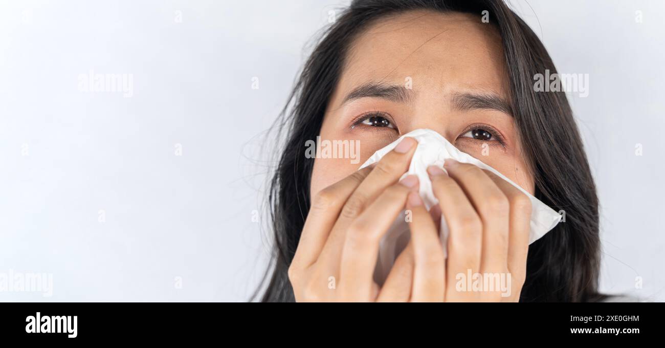 Asian woman, unhappy patient using a tissue to sneeze and blowing her ...