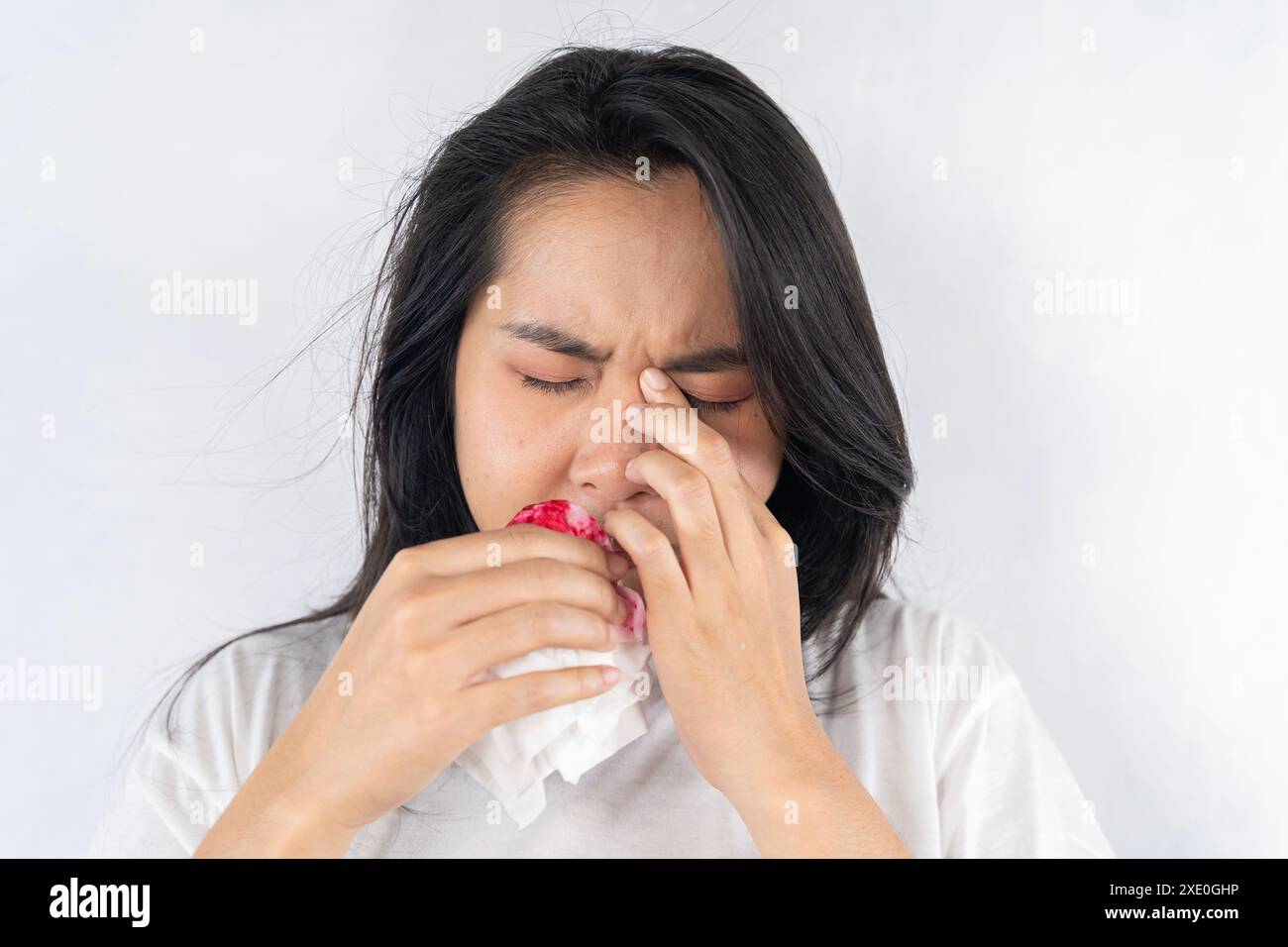 Asian women in satin nightwear with Nosebleed or Epistaxis against gray background, Nasal cavity ...