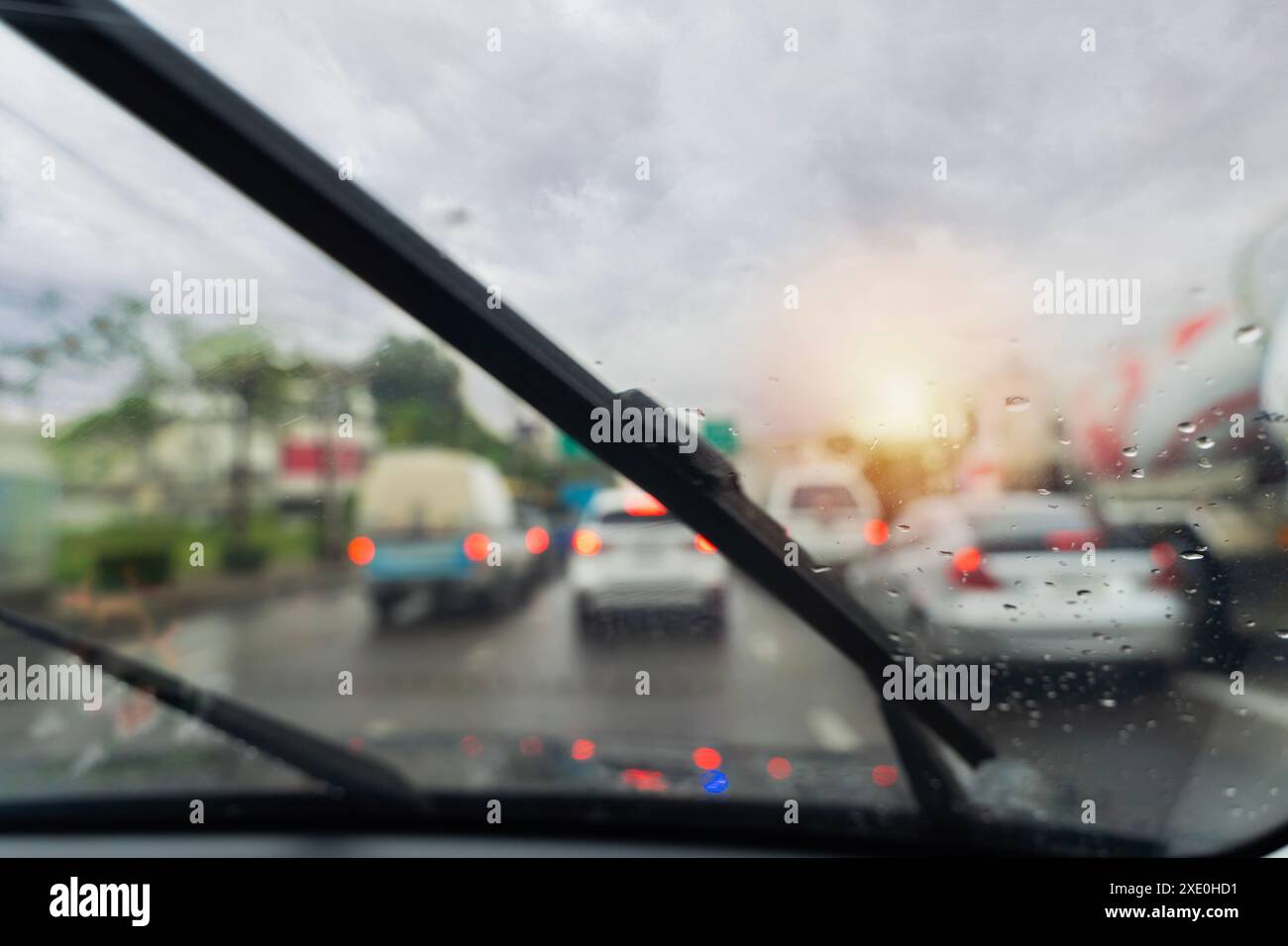A car windshield is covered in raindrops and the wipers are in motion ...