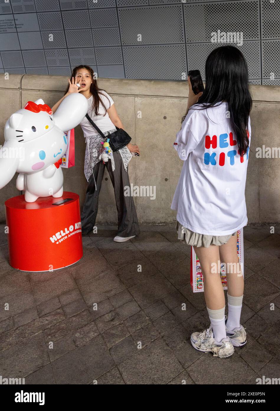 girl photographing another beside Sanrio character, Hello Kitty 50th ...