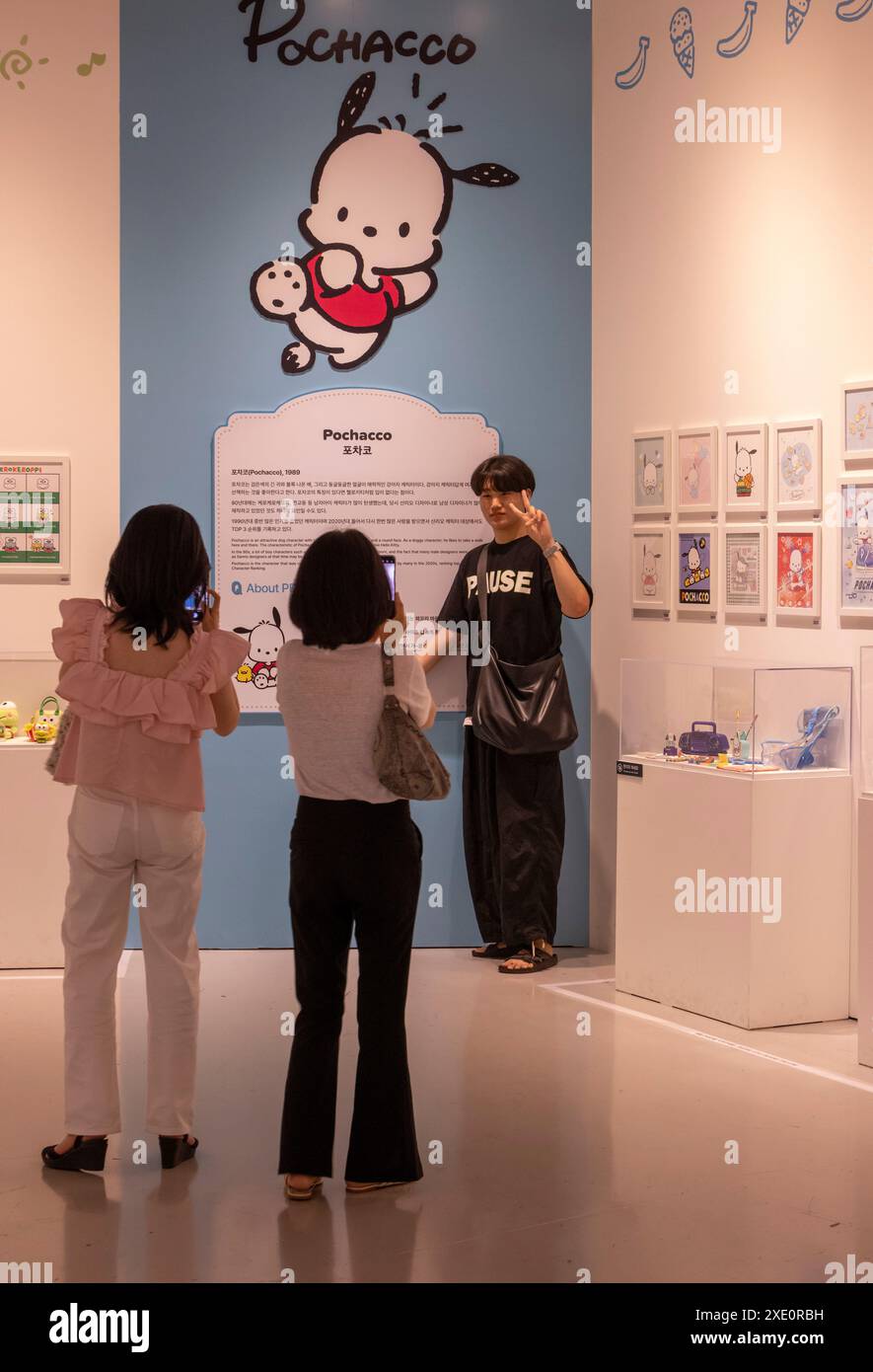 two girls taking souvenir photo of boy with Pochacco, Hello Kitty 50th ...