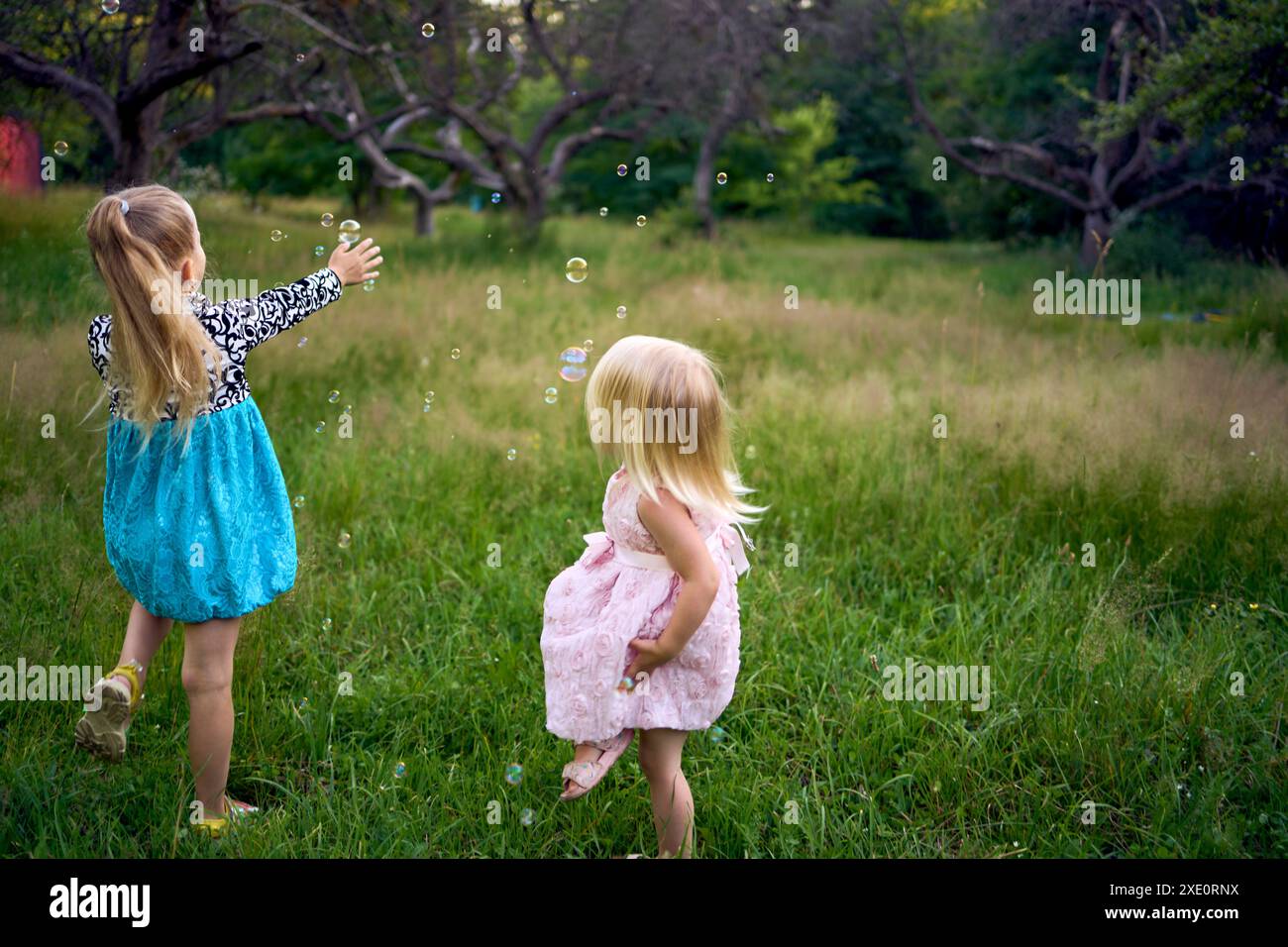child and toddler, sisters, catching bubbles in the garden Stock Photo ...