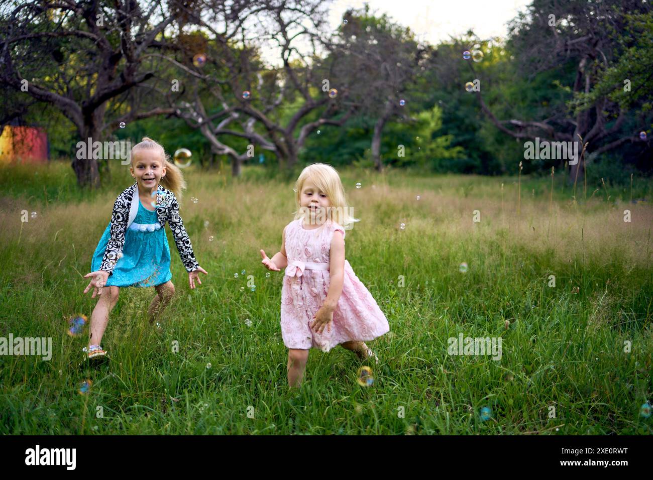 child and toddler, sisters, catching bubbles in the garden Stock Photo ...