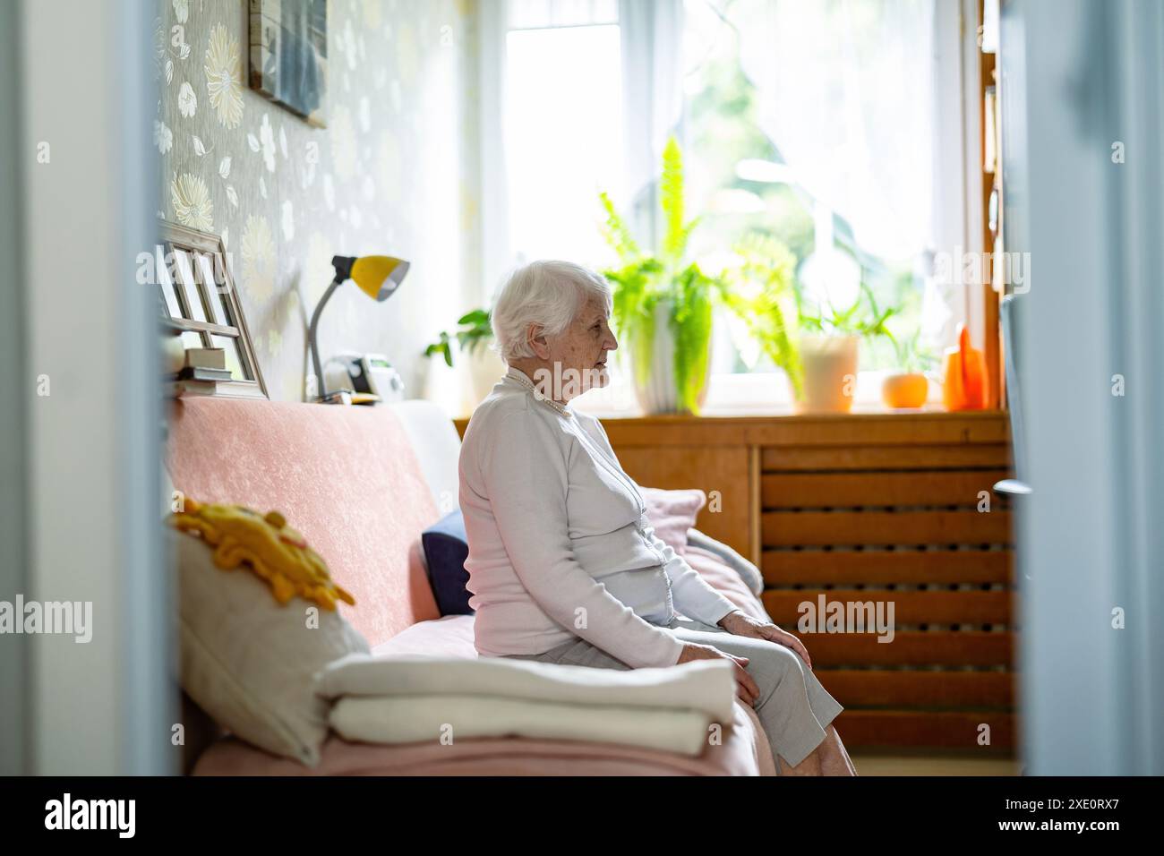 Elderly woman sitting alone on a bed in nursing home Stock Photo - Alamy