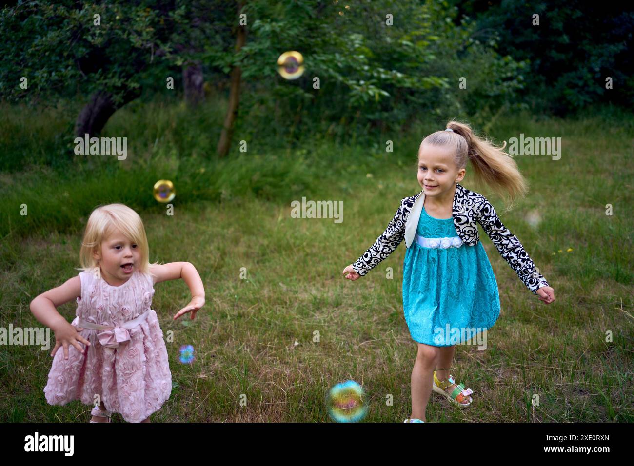 child and toddler, sisters, catching bubbles in the garden Stock Photo ...