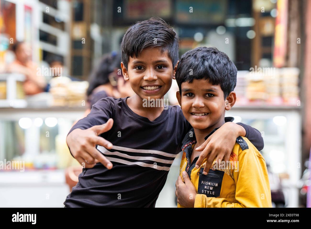 Two young indian boys pose for camera with smiles making hand gesture ...