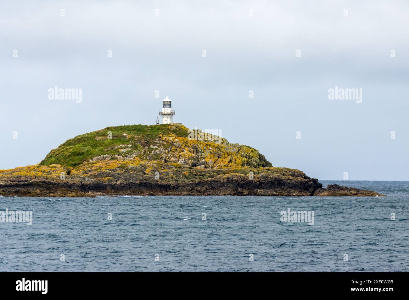 Small white lighthouse on rocky island in the ocean Stock Photo - Alamy