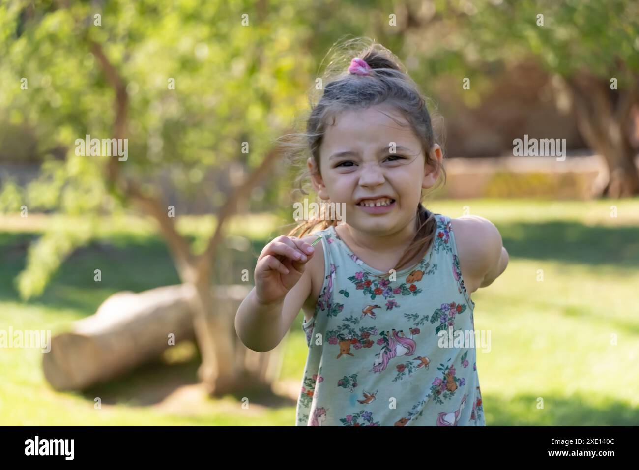 Little girl with a mischievous face runs towards the camera, making ...