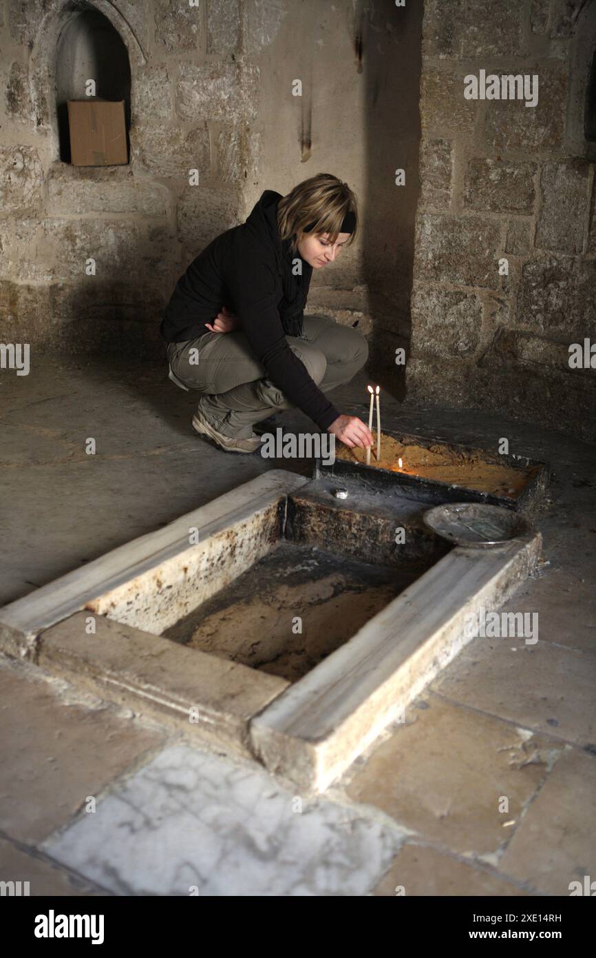 Catholic lady lights a candle in the Chapel or Aedicule of Ascension at ...
