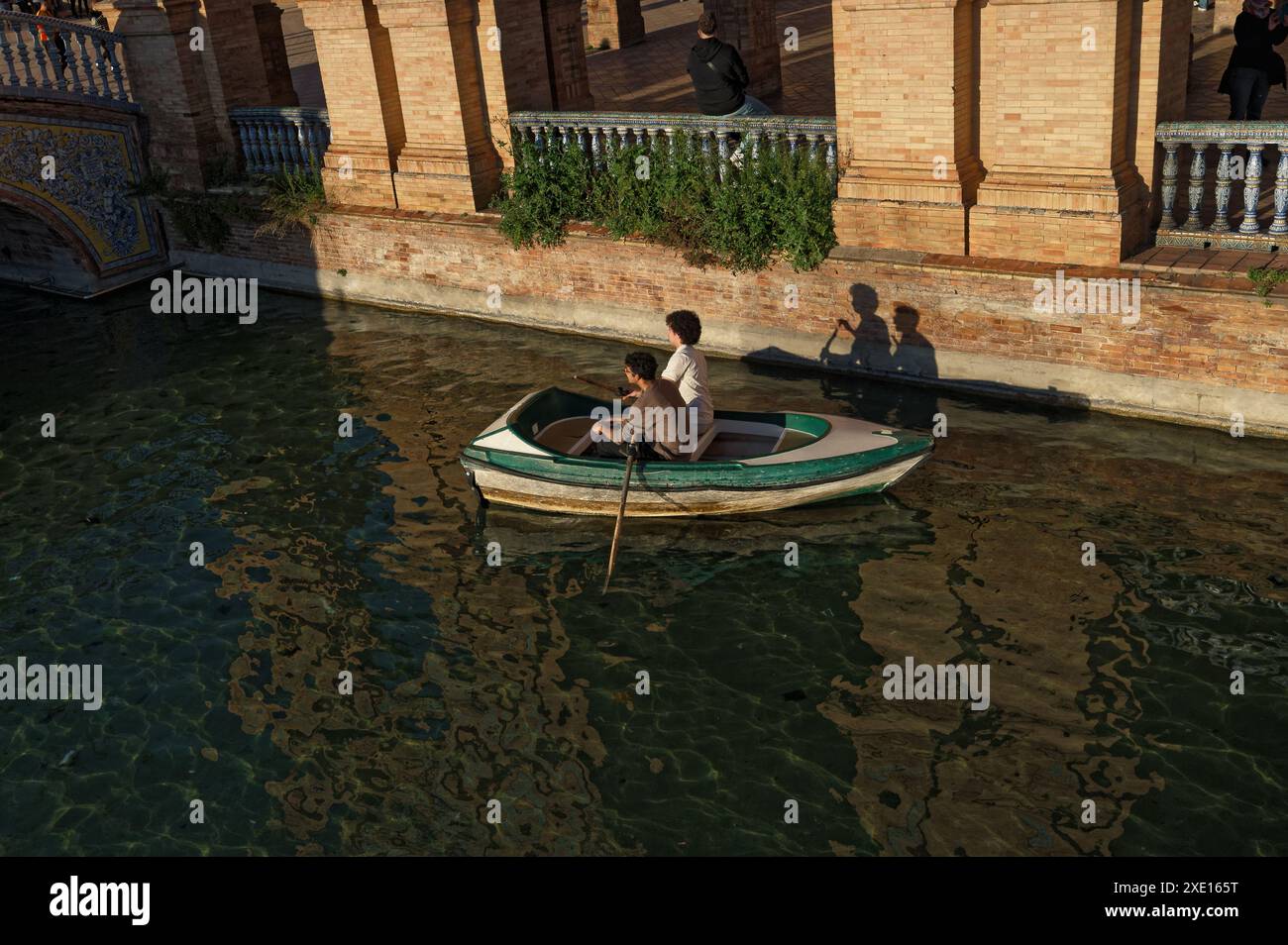 Two people rowing a boat along the canal of Plaza de España in Sevilla ...