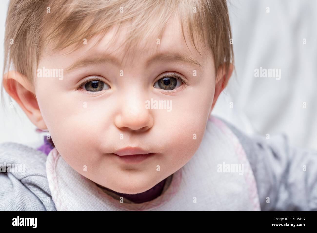 Sweet baby girl captures attention with direct eye contact, wearing an ...
