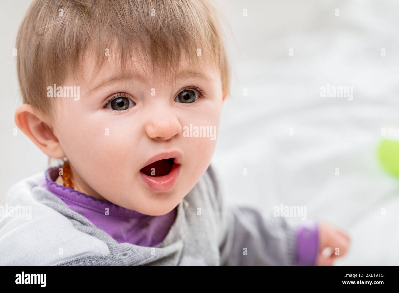 Surprised baby girl in a close up portrait, looking up with wide eyes ...