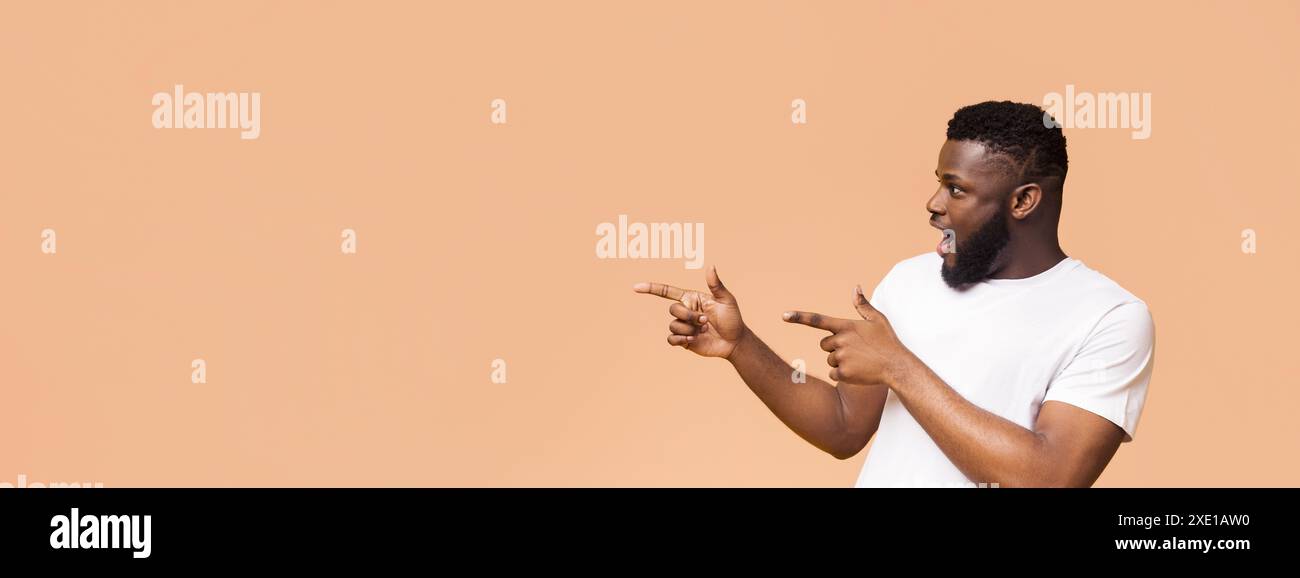 Surprised Man Pointing To The Right On A Peach Background Stock Photo ...