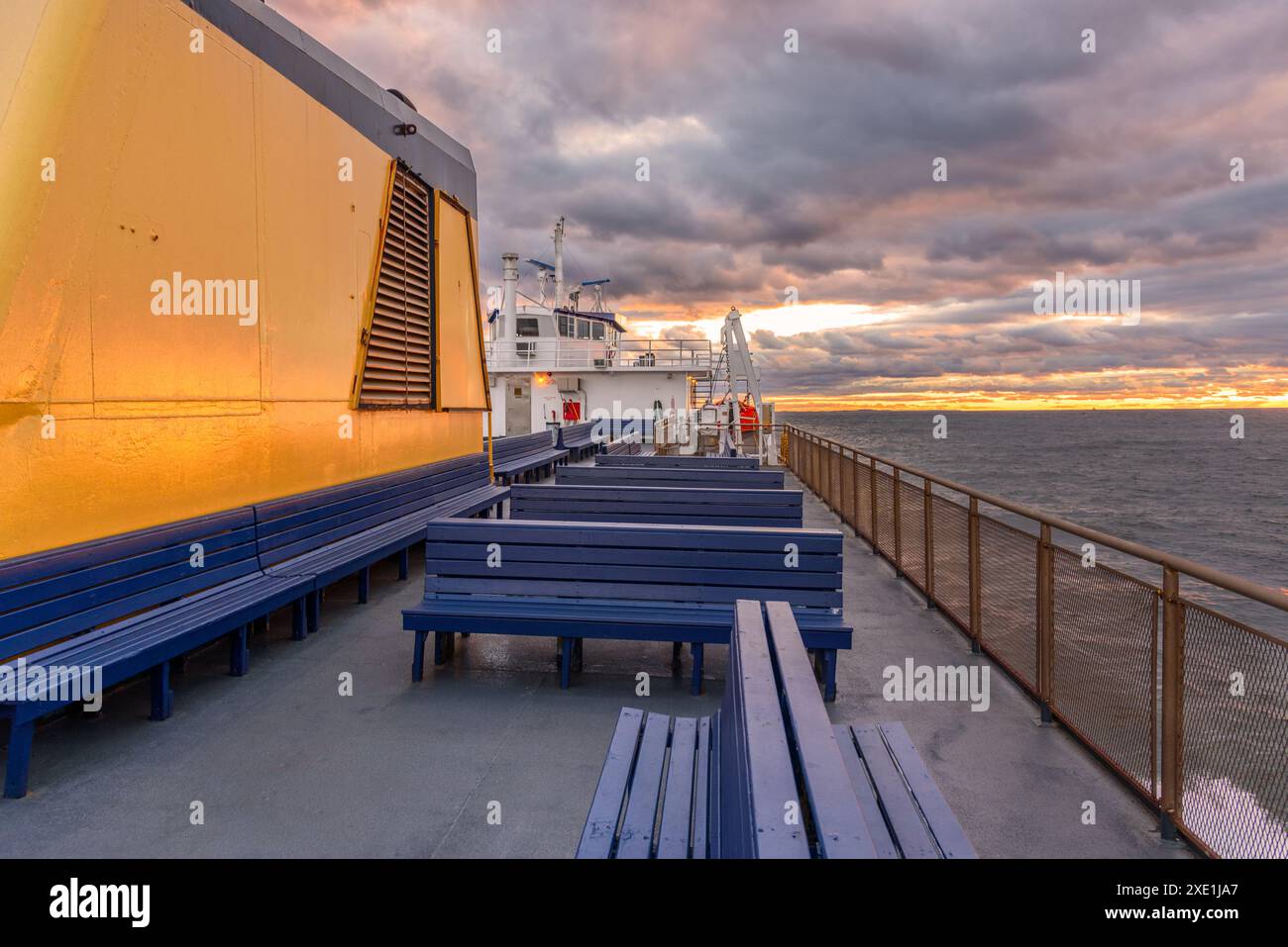 Empty wwoden benches on the top open deck of a ferry sailing under ...