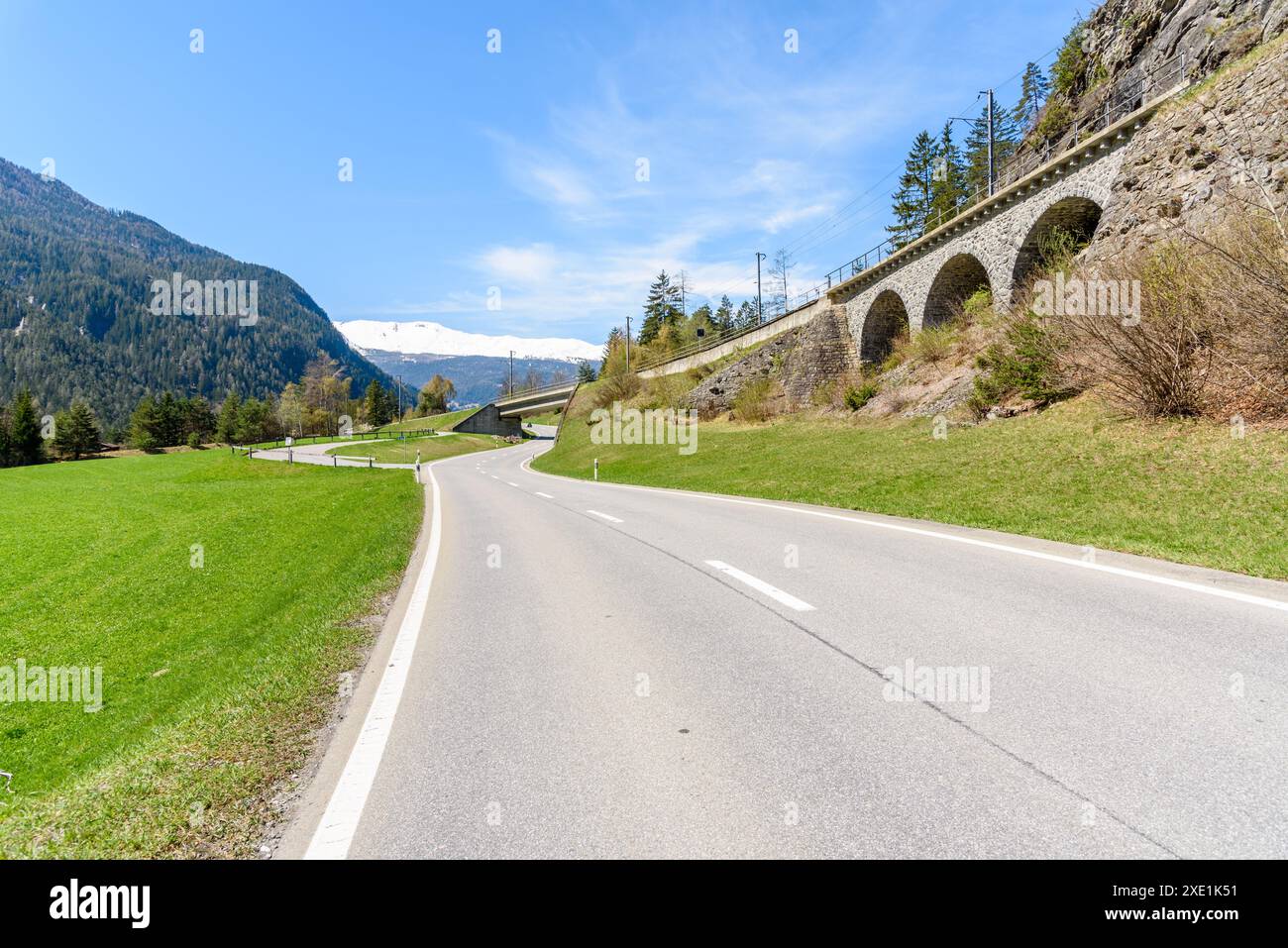 Deserted winding road through a valley passing under a railway in the ...