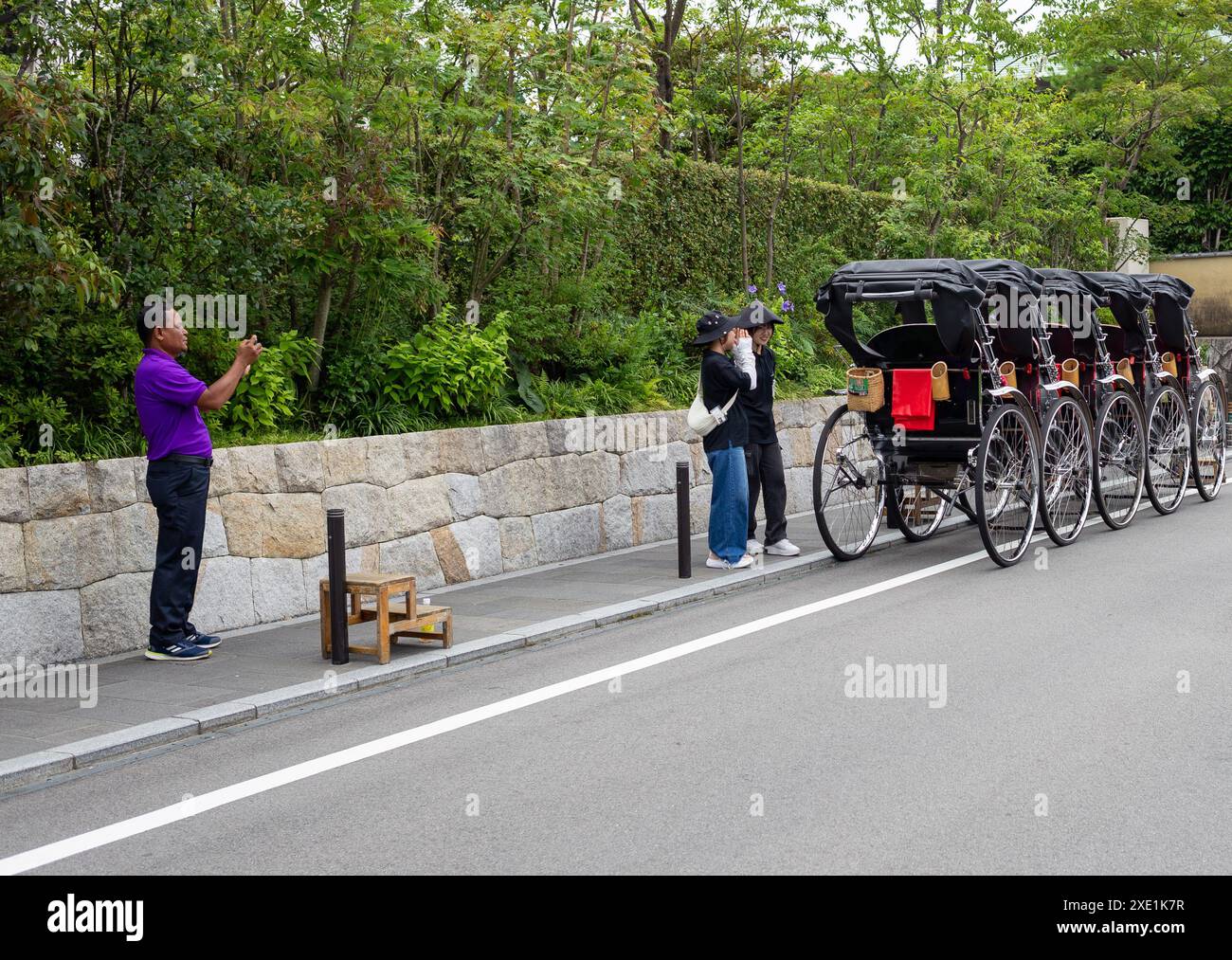 A tourist takes photos of a Jinrikisha cart in the Arashiyama area of ...