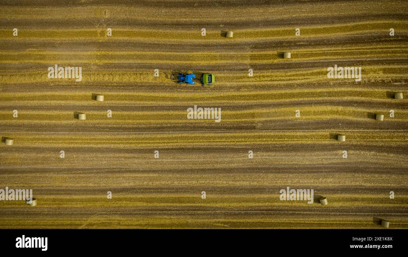 Aerial view from tractor as it pulling round baler, machine that rolls ...