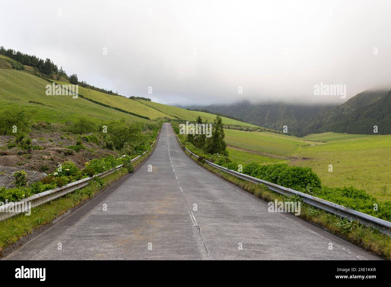 A long road with a grassy hillside in the background Stock Photo - Alamy