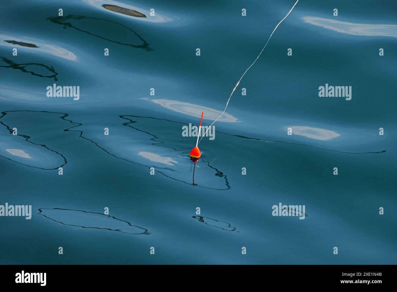 Fishing rod float in blue sea water Stock Photo - Alamy