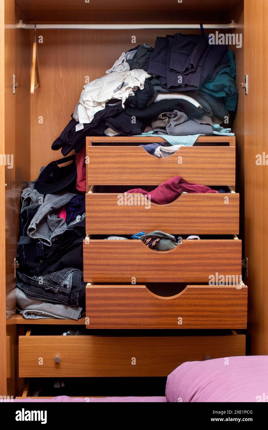 Cluttered wooden wardrobe with disorganized clothing - a concept of ...