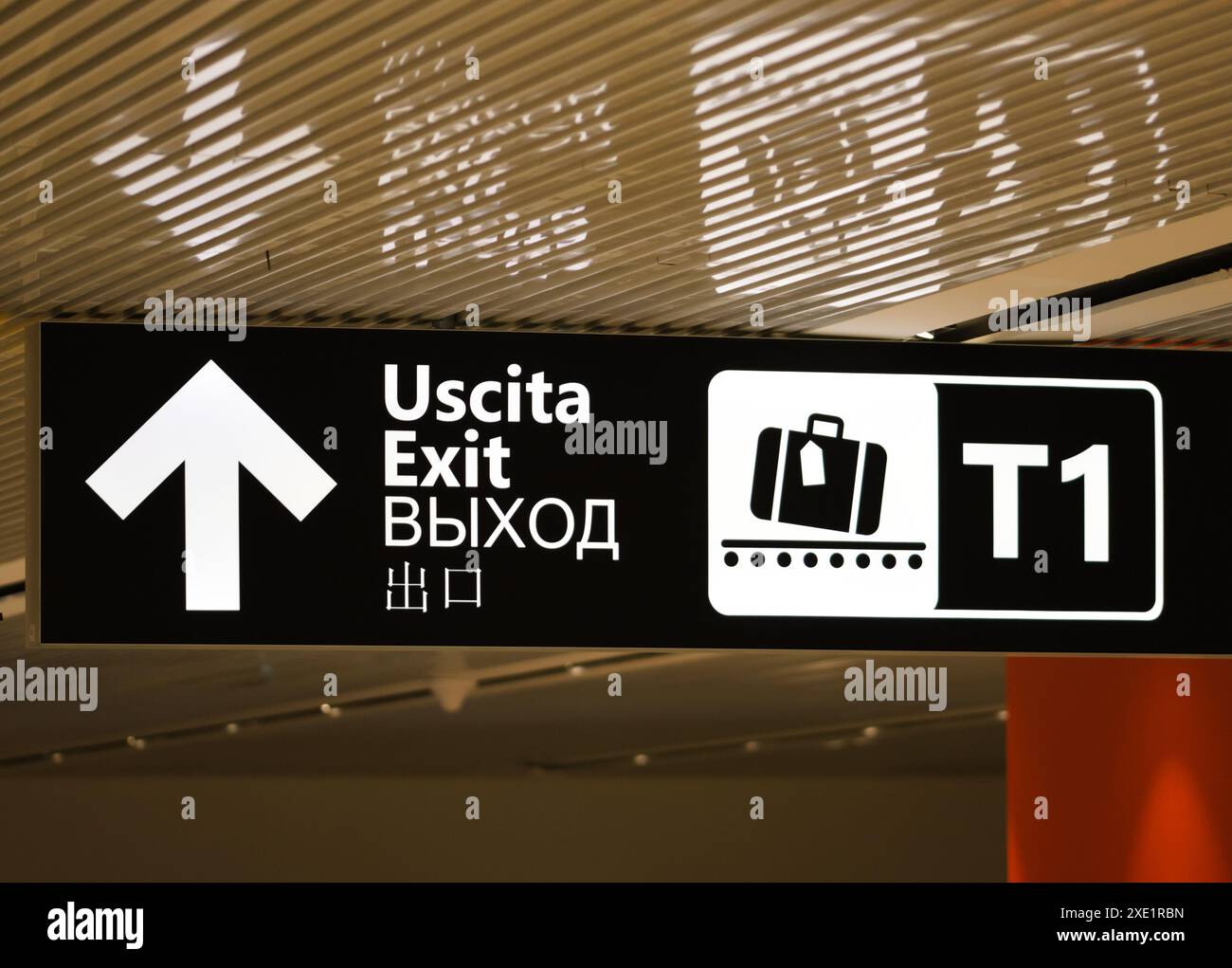 Information signboard at an airport, showing "Exit" in italian, english ...