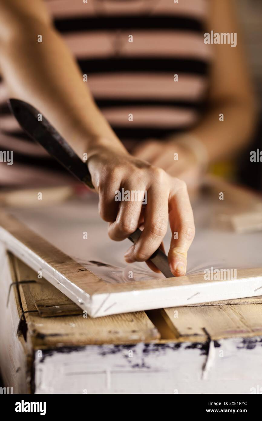 Close-up of a female painter's hand delicately using a palette knife on ...