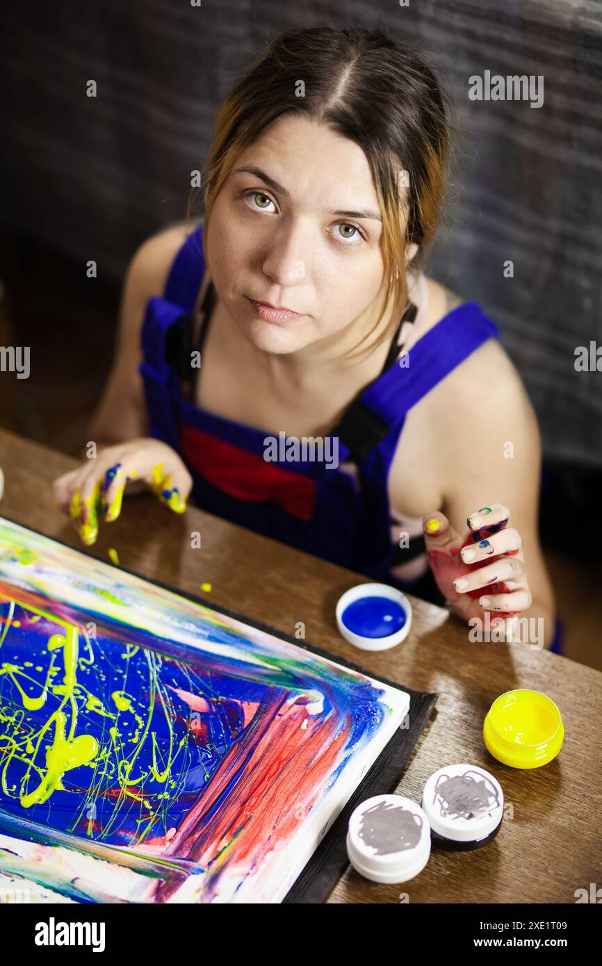 A focused woman artist in her studio uses bold colors to create an ...