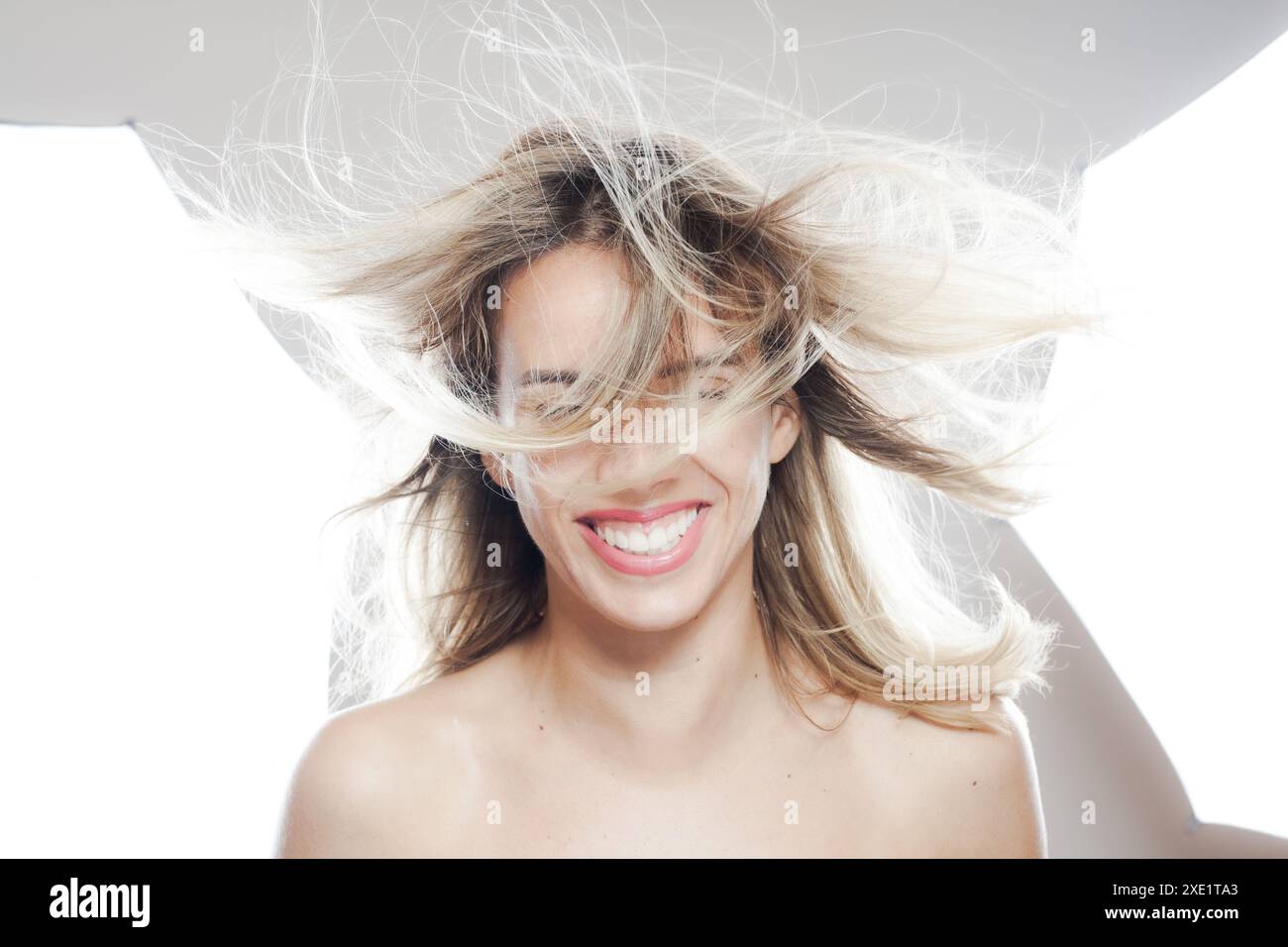 An exuberant young woman beams with a dazzling smile, her hair blown ...