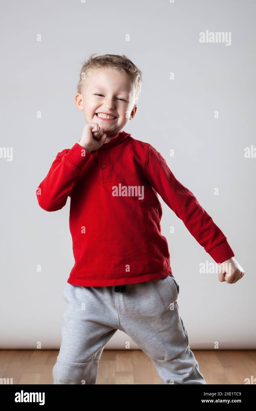Portrait of a happy little boy standing upright smiling and looking at ...
