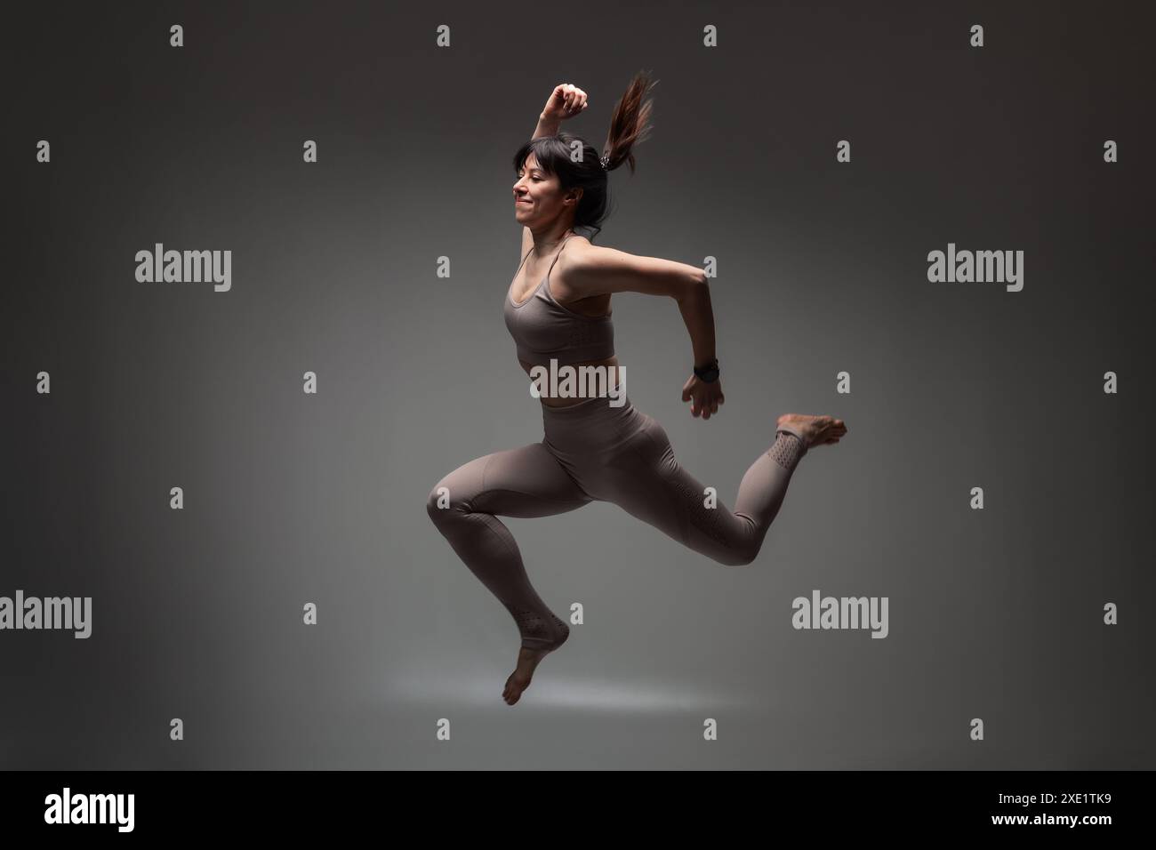 A young woman captured in a powerful mid-air leap, exuding strength and ...