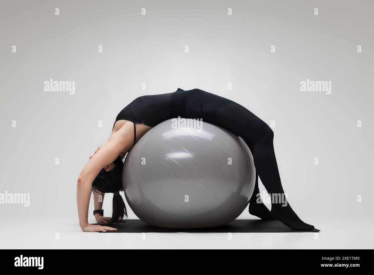 A young woman demonstrates flexibility and strength as she bends over a ...