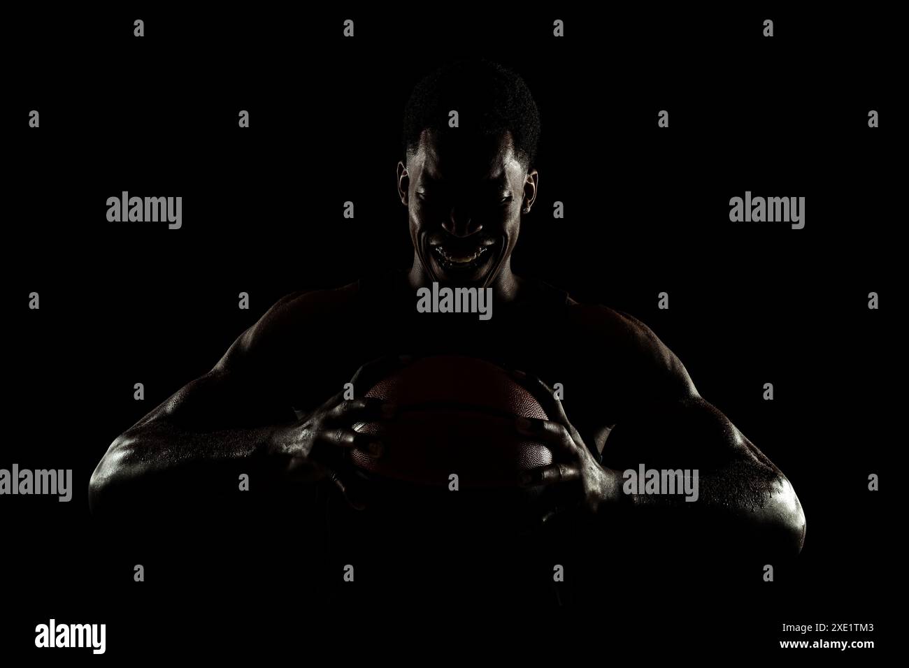 Basketball player holding a ball against black background. Distressed ...