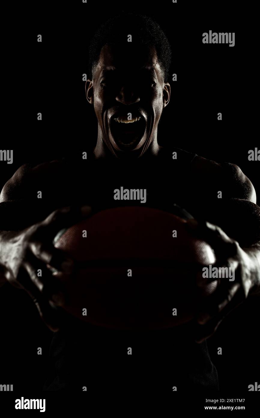 Basketball player holding a ball against black background. Distressed ...