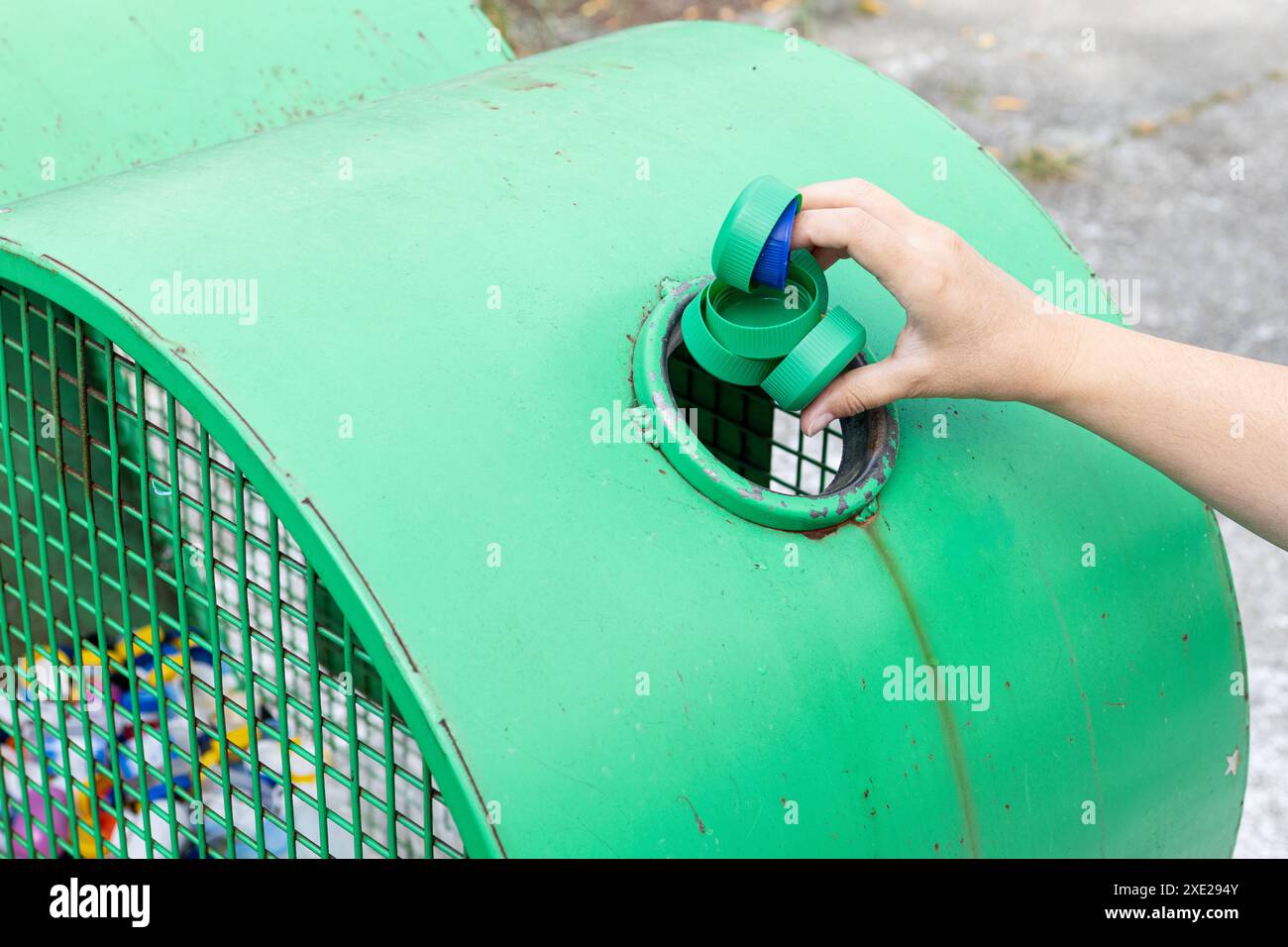 Hand throwing plastic caps into a urban recycling bin. Environment and ...