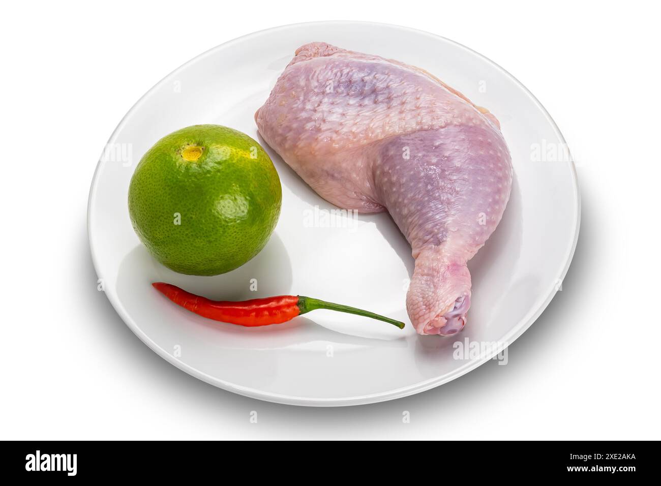 Fresh raw chicken leg with a green lemon and red chilli in a white ...