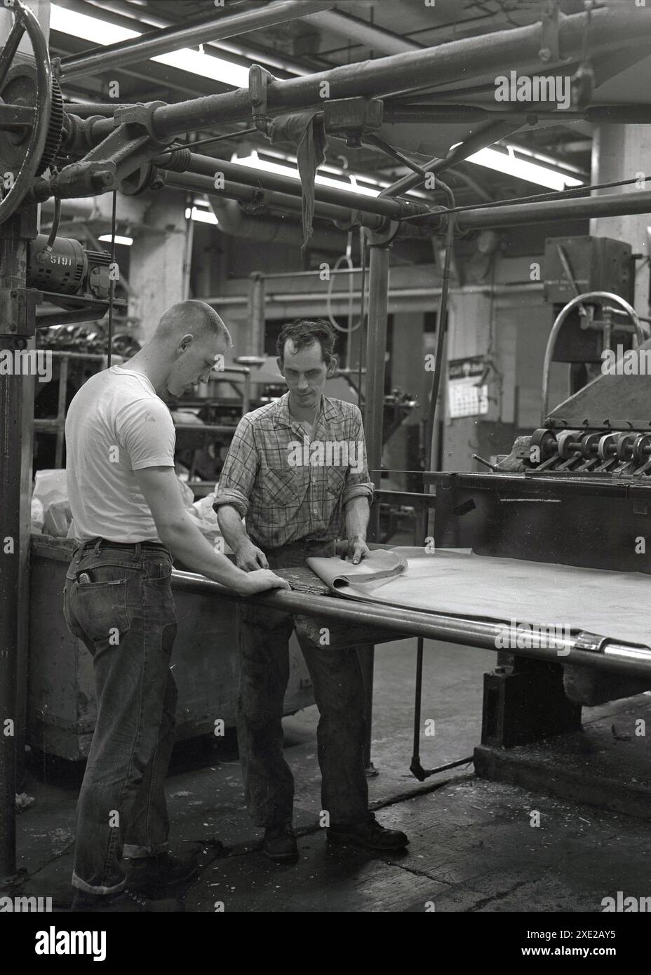 1950s, historical, two male workers checking large sheets of paper by a ...